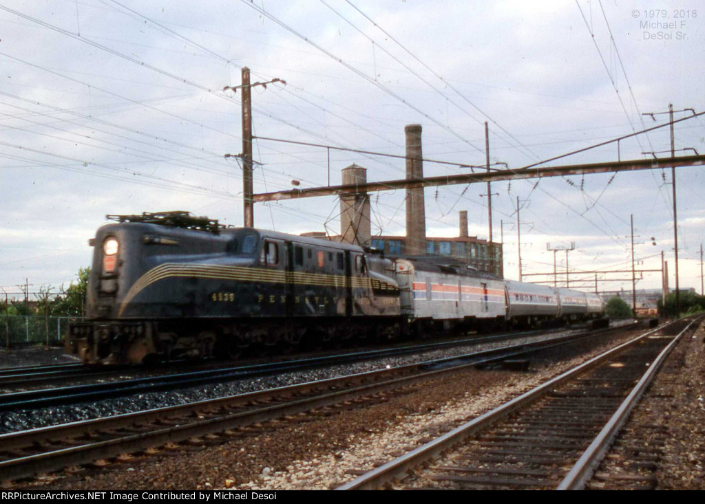Painted in PRR colors, Amtrak GG-1 #4935 leads a westbound through the station at Frankford ...